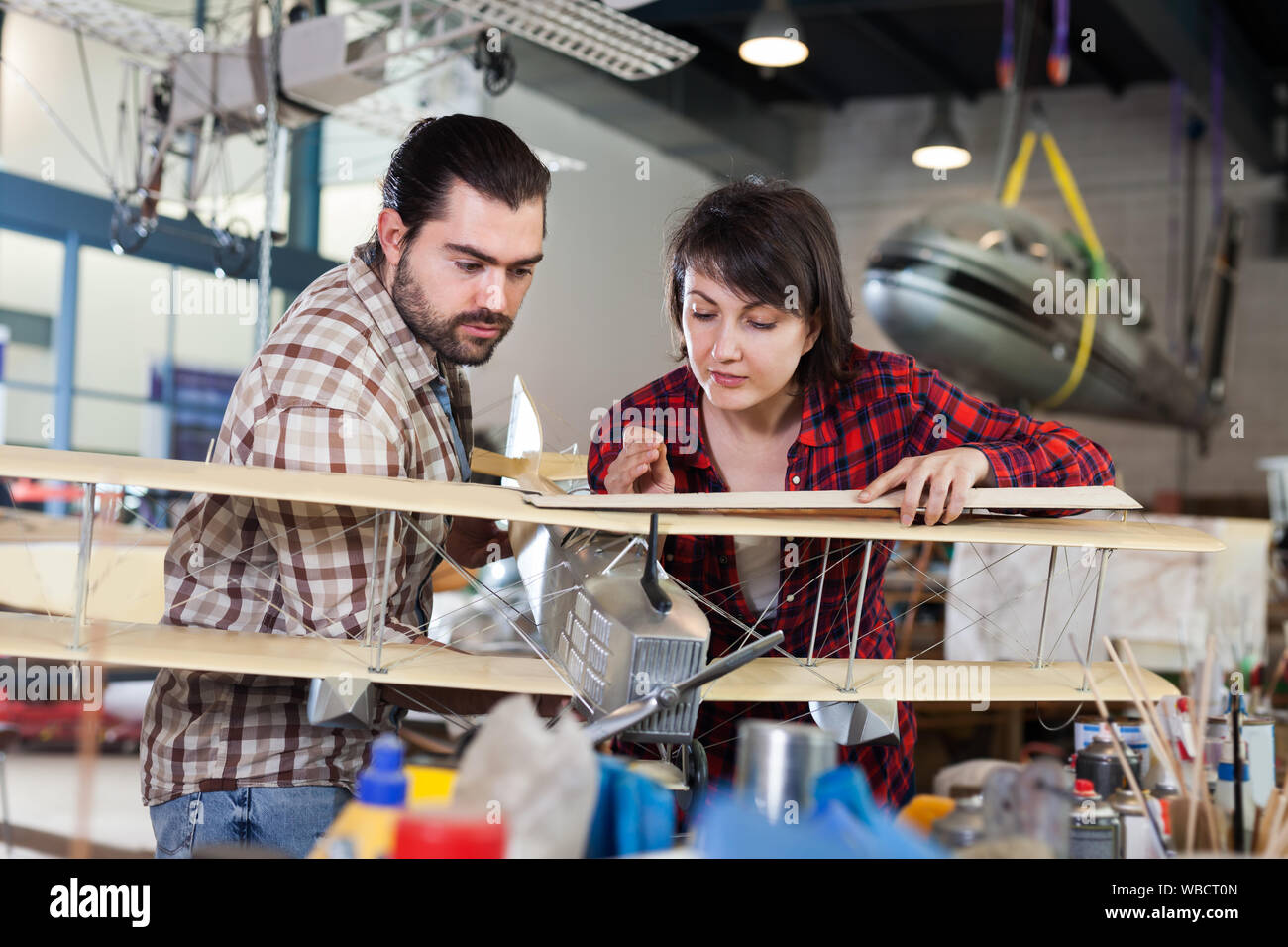 Positive female and male hobbyists engaged in creating plane models in ...