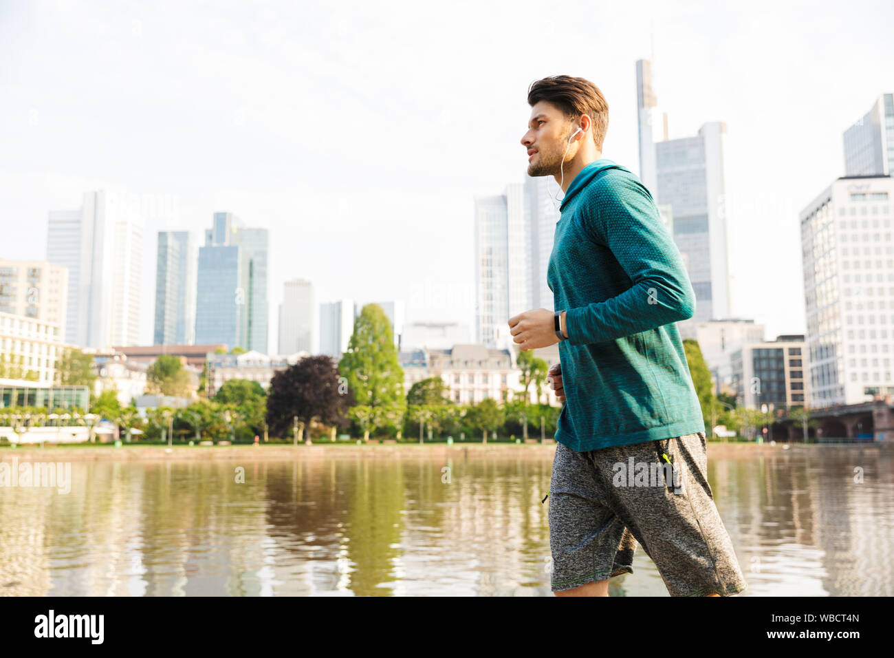 Image of a concentrated young strong sportsman runner running outdoors ...