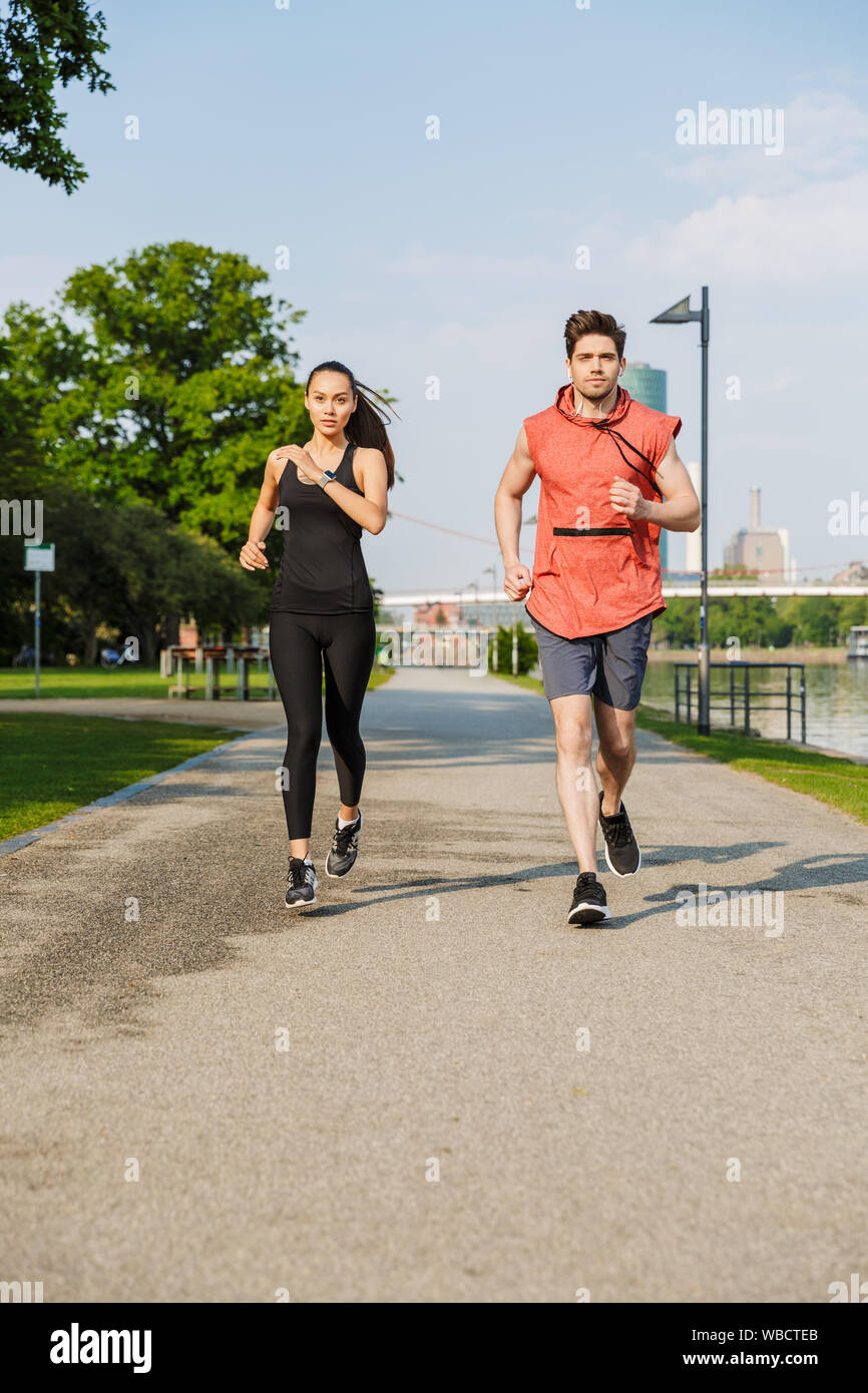 Photo of athletic serious man and woman wearing sportswear doing ...