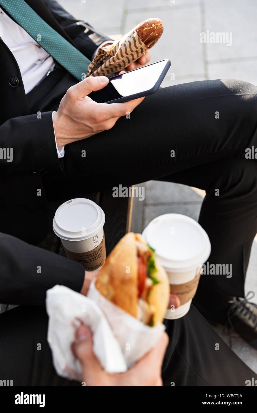 Close up of two young businessmen wearing suits having a lunch break ...