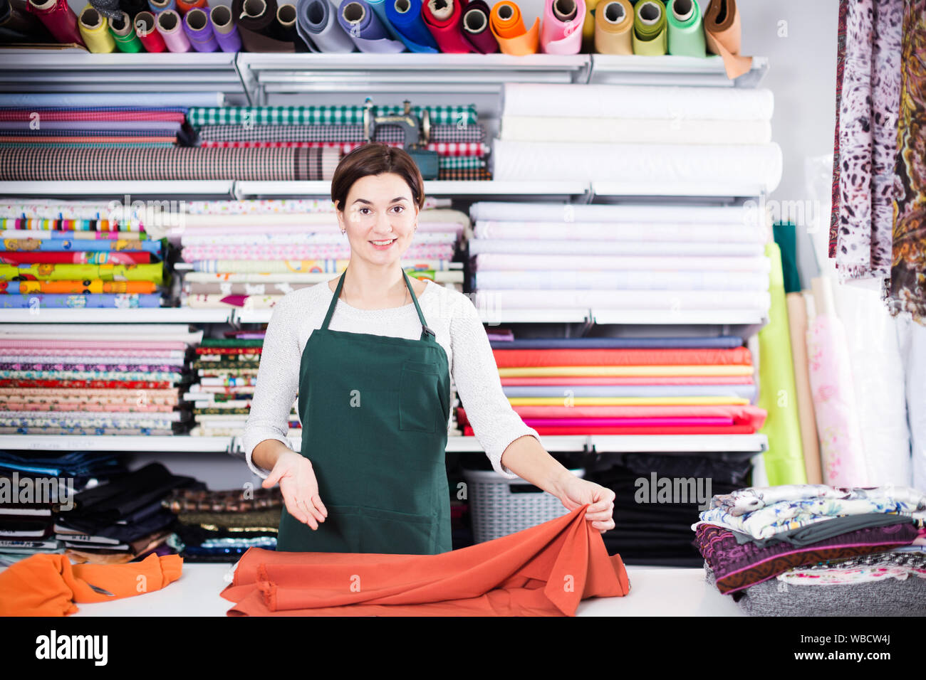 Female shop assistant measuring piece of cloth at drapery shop Stock ...