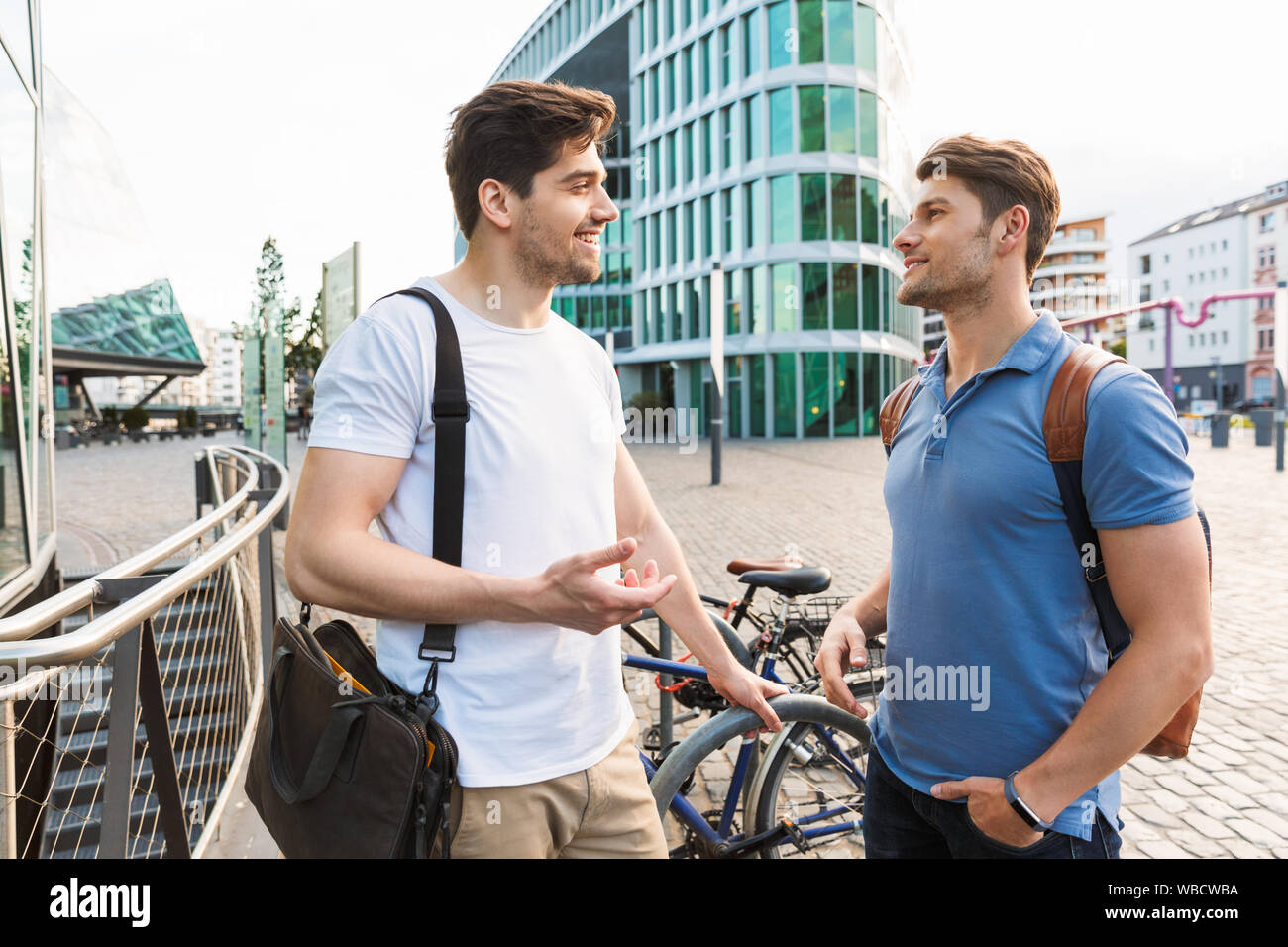Two smiling young men friends dressed casually spending time together ...