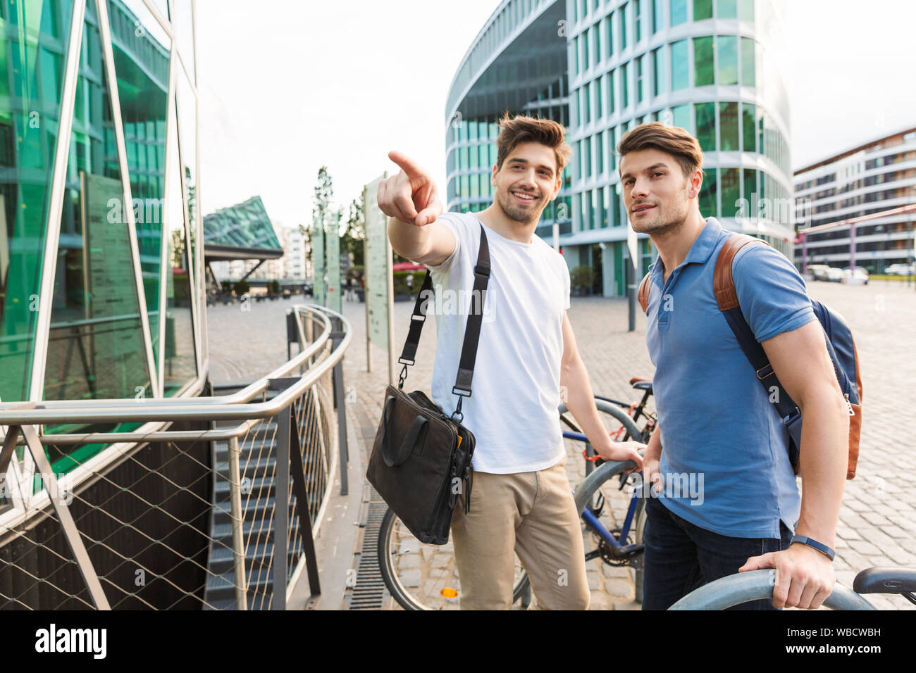 Two smiling young men friends dressed casually spending time together ...
