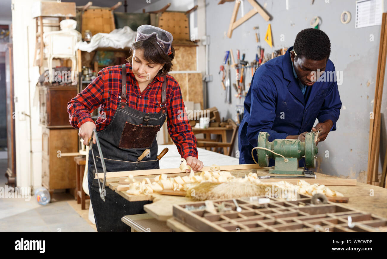 Woman and man carpenters using tools for restoration wooden chair in ...