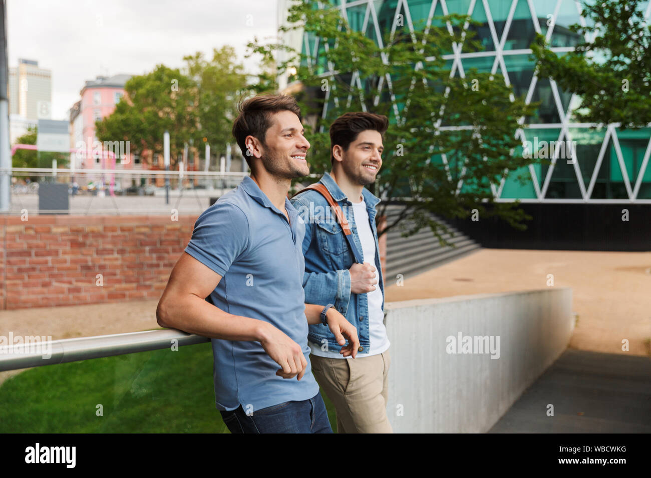 Two smiling young men friends dressed casually spending time together ...
