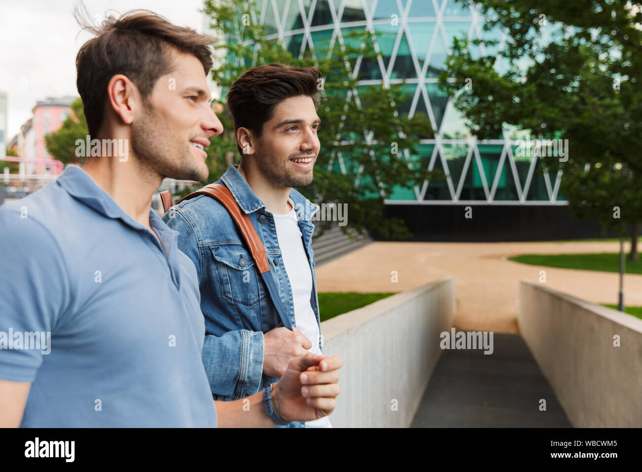 Two smiling young men friends dressed casually spending time together ...