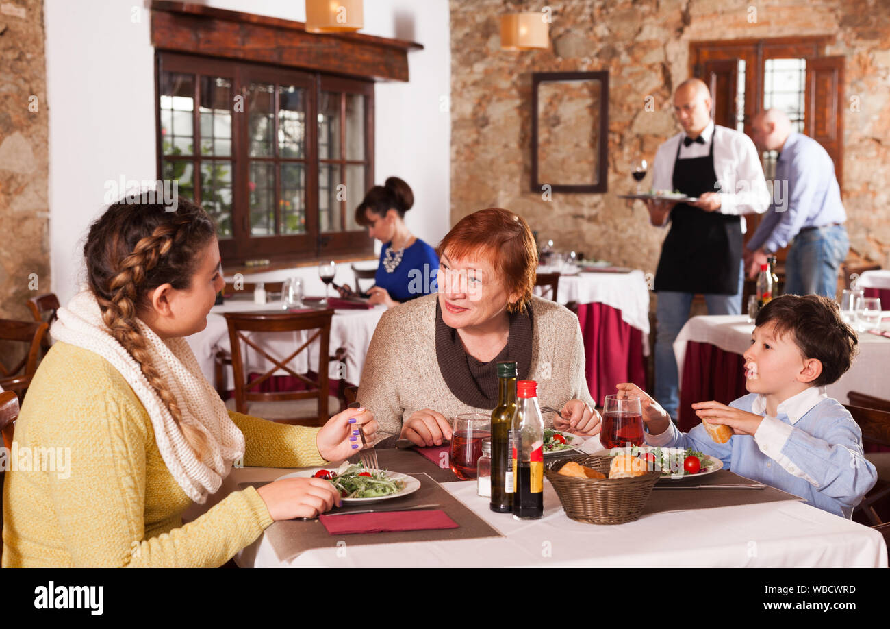 Portrait of two happy women with little boy having dinner in restaurant ...