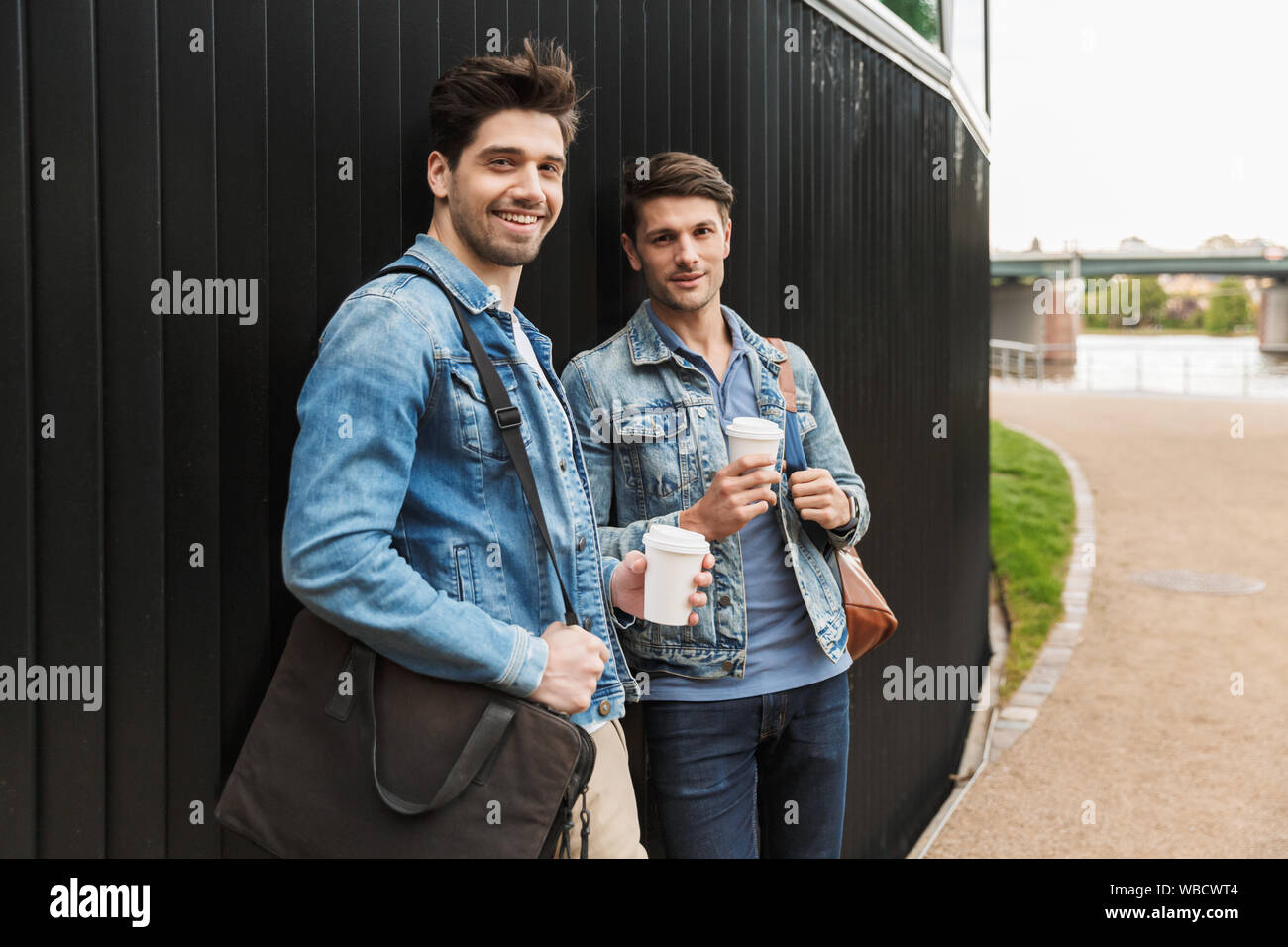 Two smiling young men friends dressed casually spending time together ...