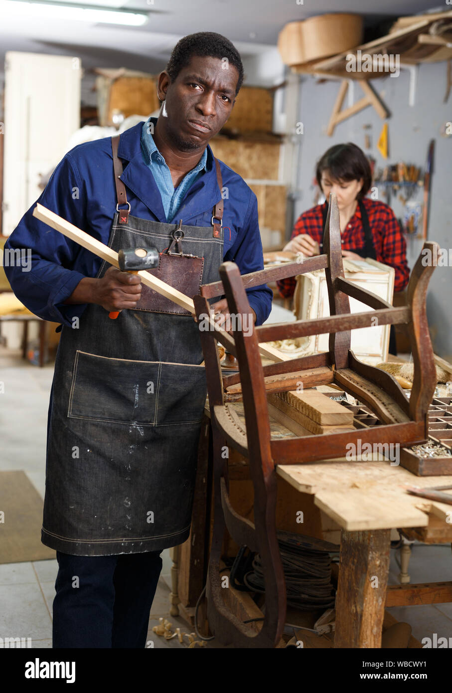 Portrait of furniture restorer in process of renewing vintage chair at ...