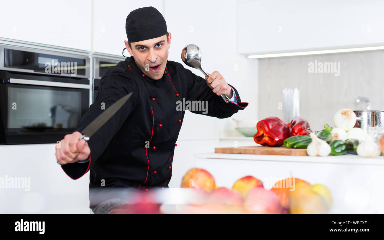 Smiling male kitchener in uniform is standing with devices in the ...