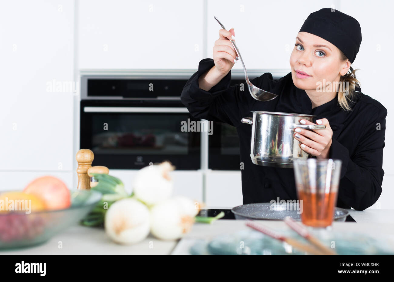 Female cook is making soup on her work place in the kitchen at the cafe ...