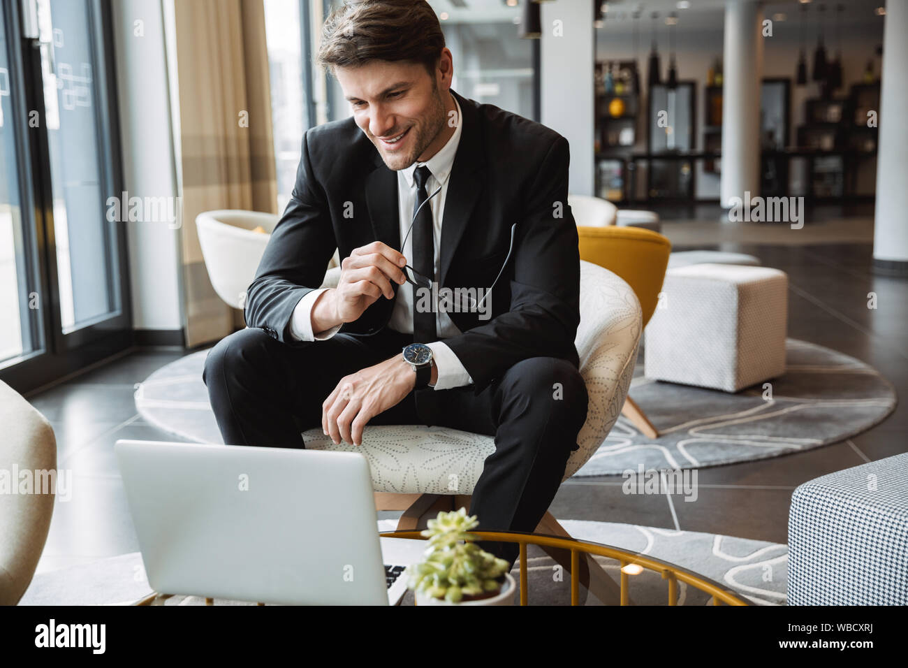 Photo of handsome businessman wearing formal black suit using laptop ...