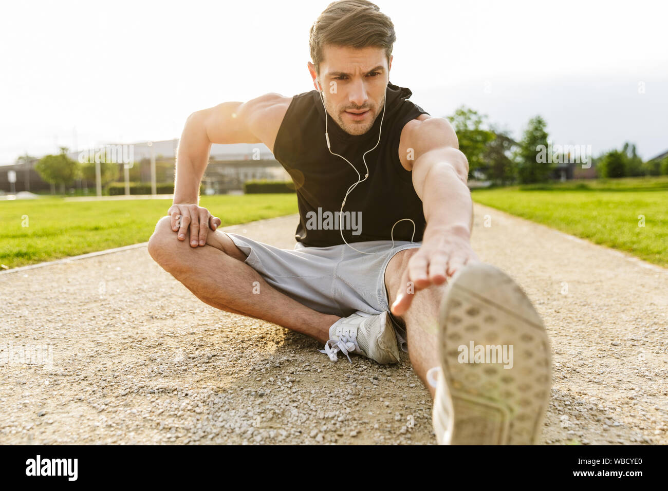 Photo of strong man in sportswear working out with earphones and ...