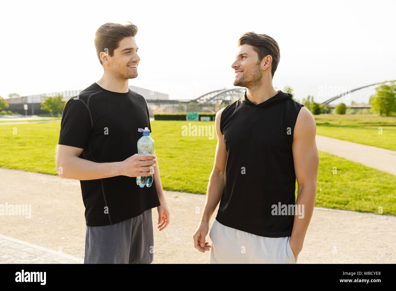Image of two athletic guys in sportswear smiling together while working ...