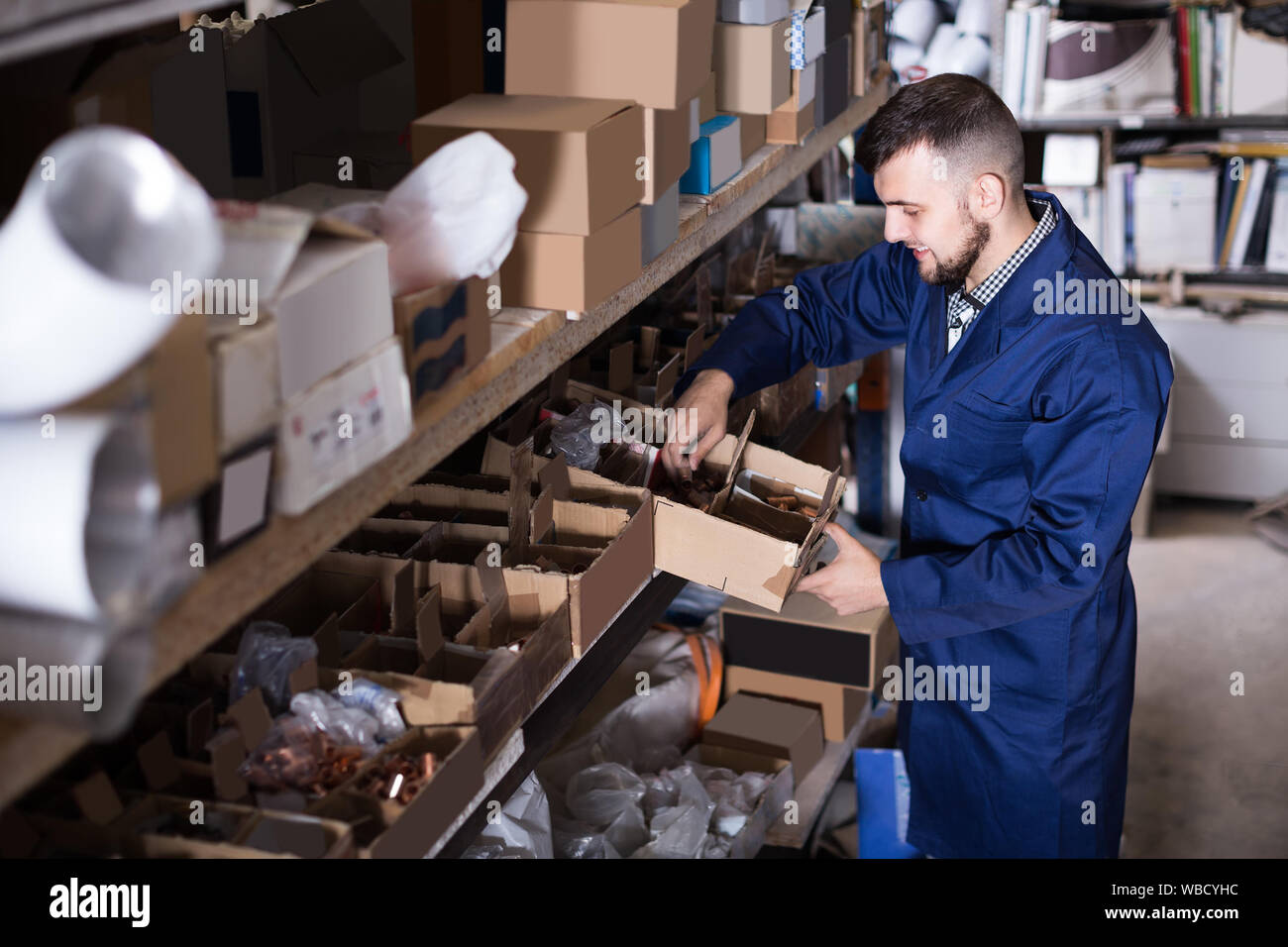 Charming man worker sorting sanitary engineering details in workshop ...