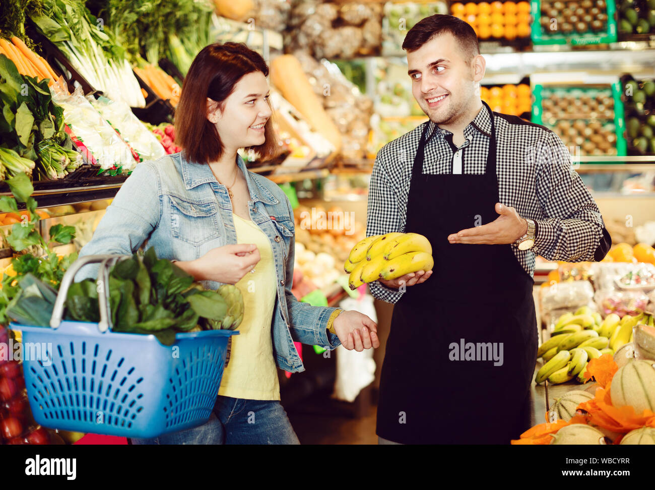 Male shopping assistant helping customer to buy fruit and vegetables in ...