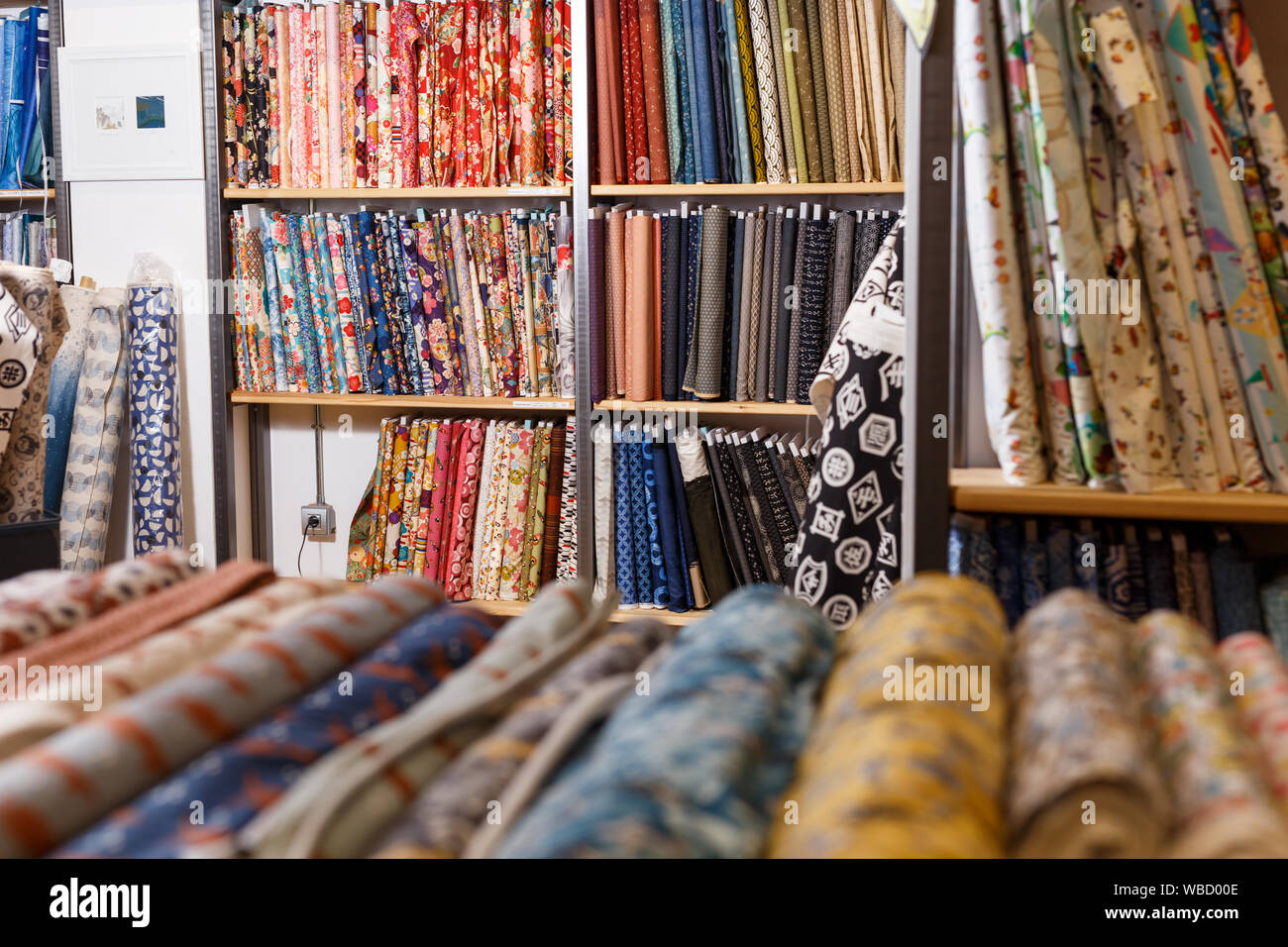 View of cloth rolls of different colors and patterns on shelves in ...