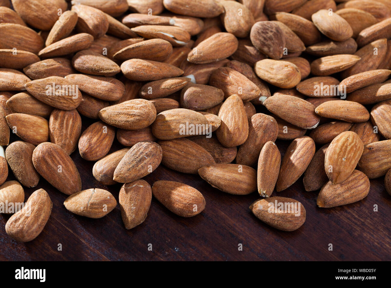 Healthy snack. Shelled roasted almond seeds on dark wood surface Stock ...