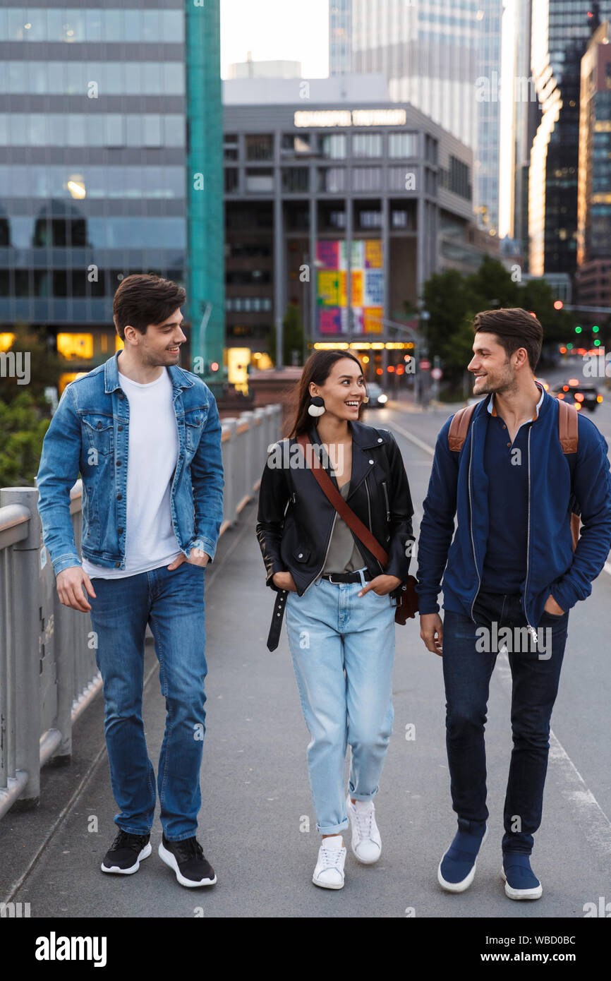 Group of cheerful young friends walking at the city streets Stock Photo ...