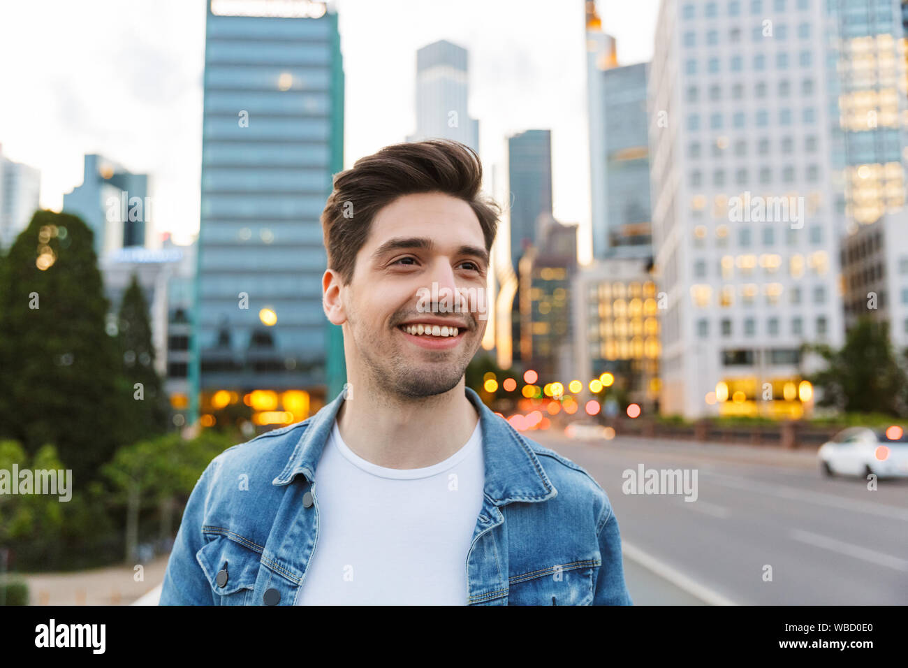 Photo of happy cheerful young man walking outdoors by street in city ...