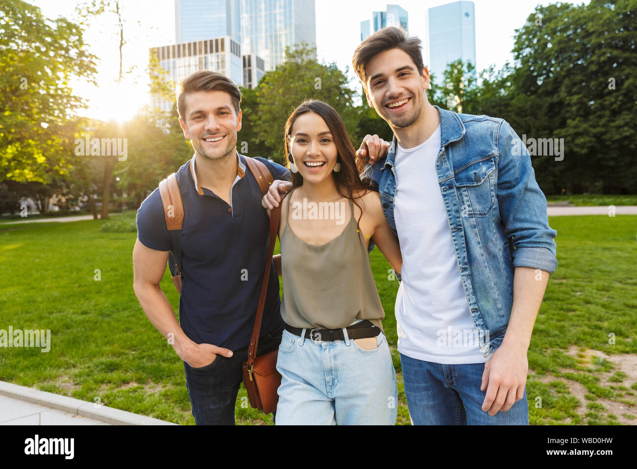 Photo of happy smiling young friends posing in nature green park ...