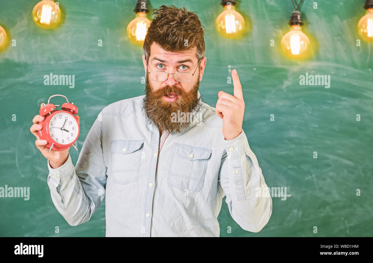Teacher in eyeglasses holds alarm clock. Discipline concept. Man with ...