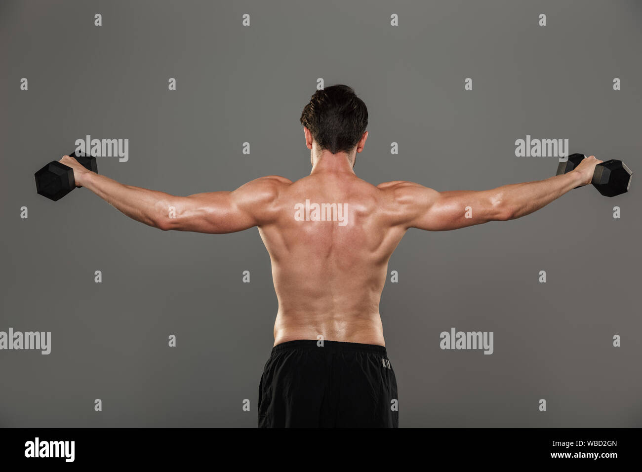 Back view of a handsome young strong sportsman posing isolated over ...