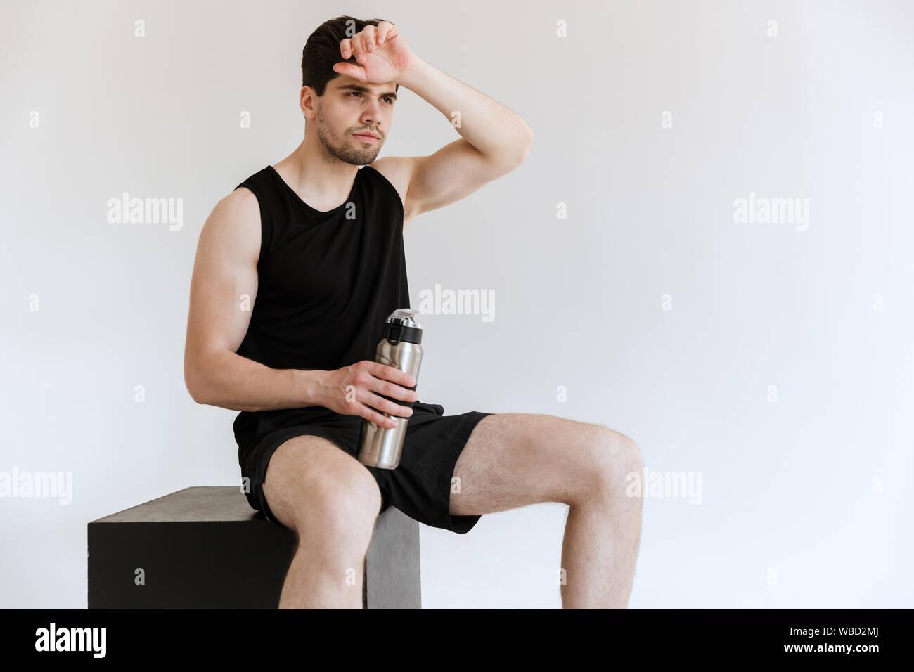 Image of a tired strong young sports man drinking water isolated over ...