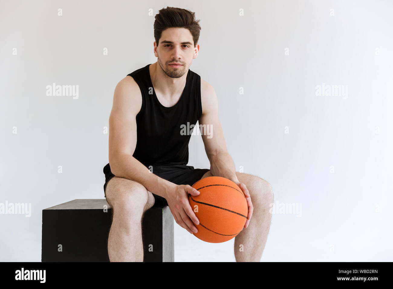 Image of a serious strong young sports man basketball player holding ...
