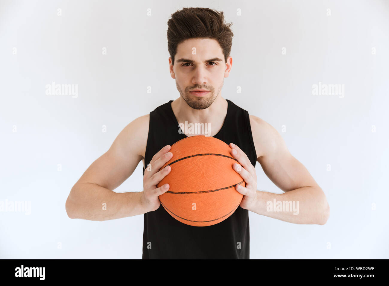 Image of a serious strong young sports man basketball player holding ...