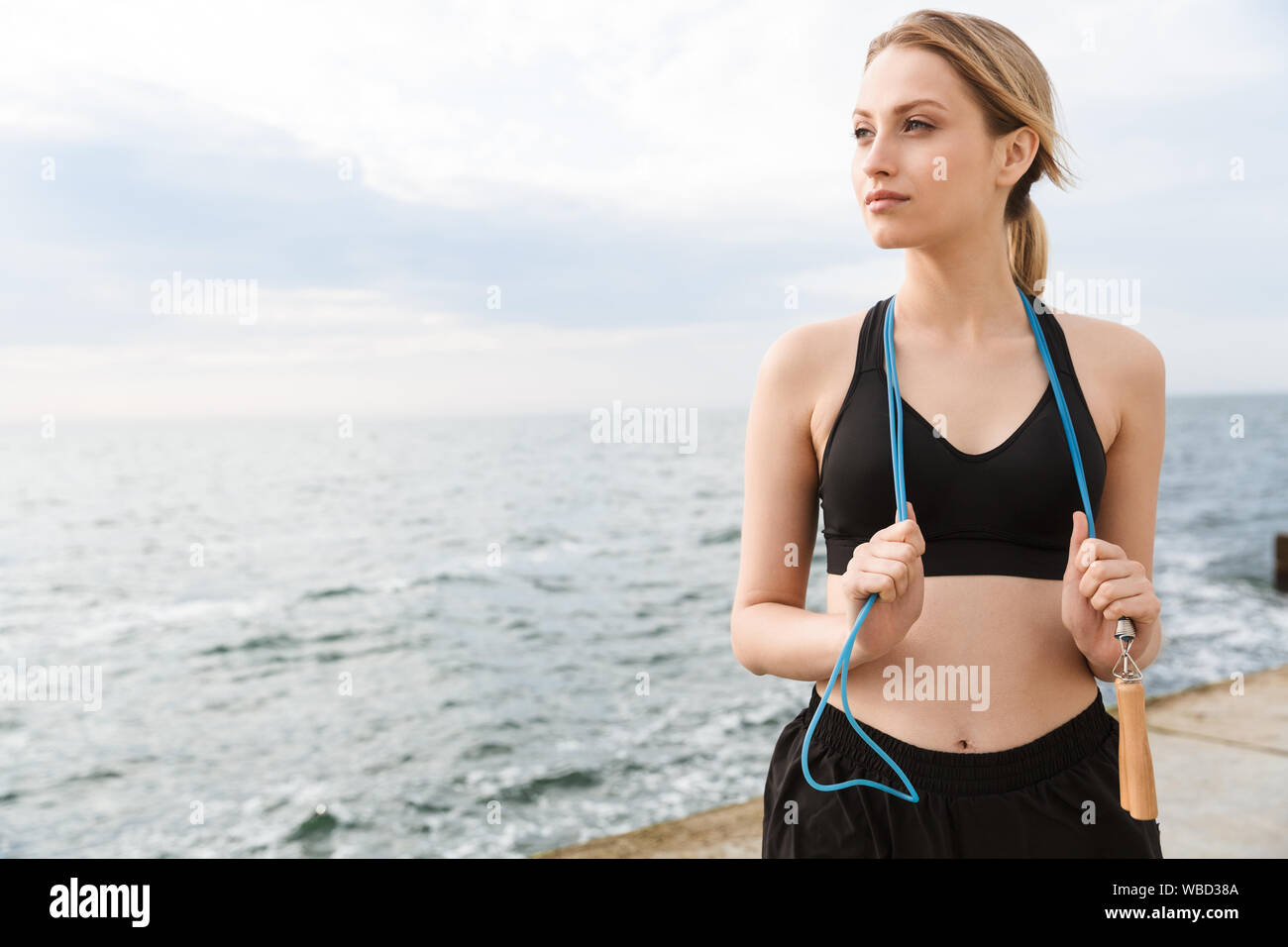 Image of attractive woman wearing tracksuit standing with jumping rope ...
