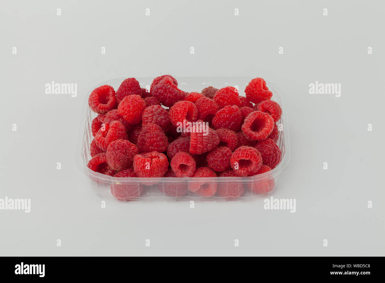 fresh raspberries in a transparent plastic packaging, on white ...