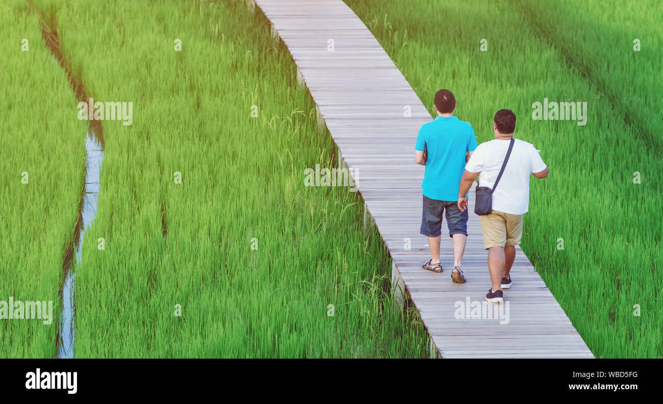Back view of two male friends walk and take photography along the ...