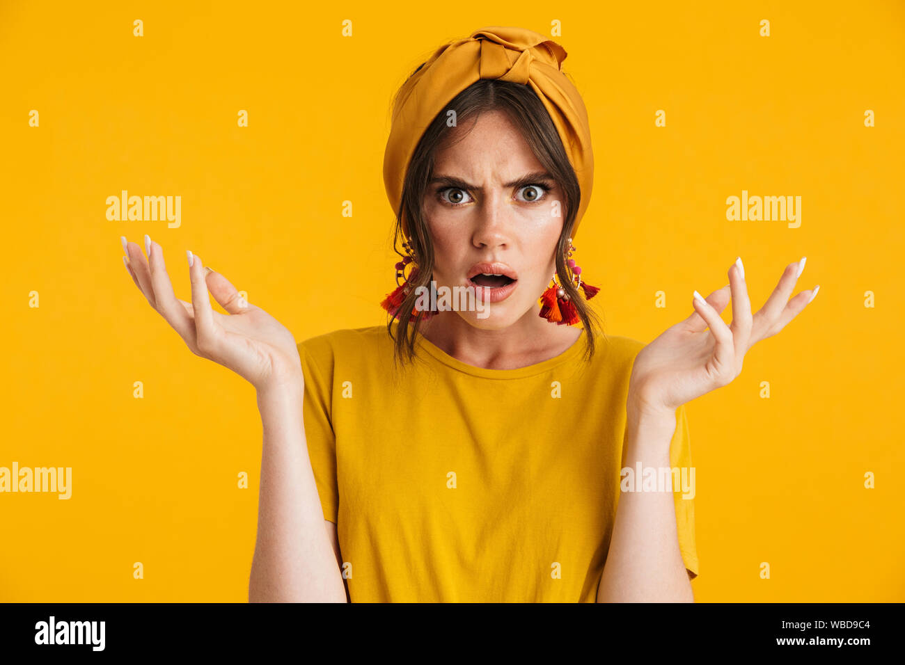 Portrait of a pretty confused young girl casually dressed standing ...