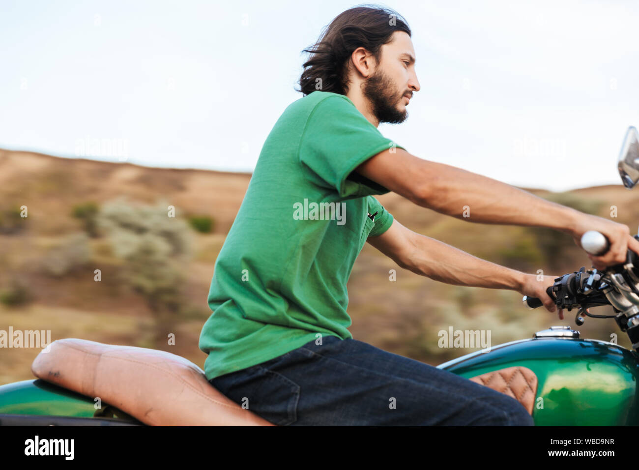 Side view of a handsome young man wearing casual outfit riding a ...