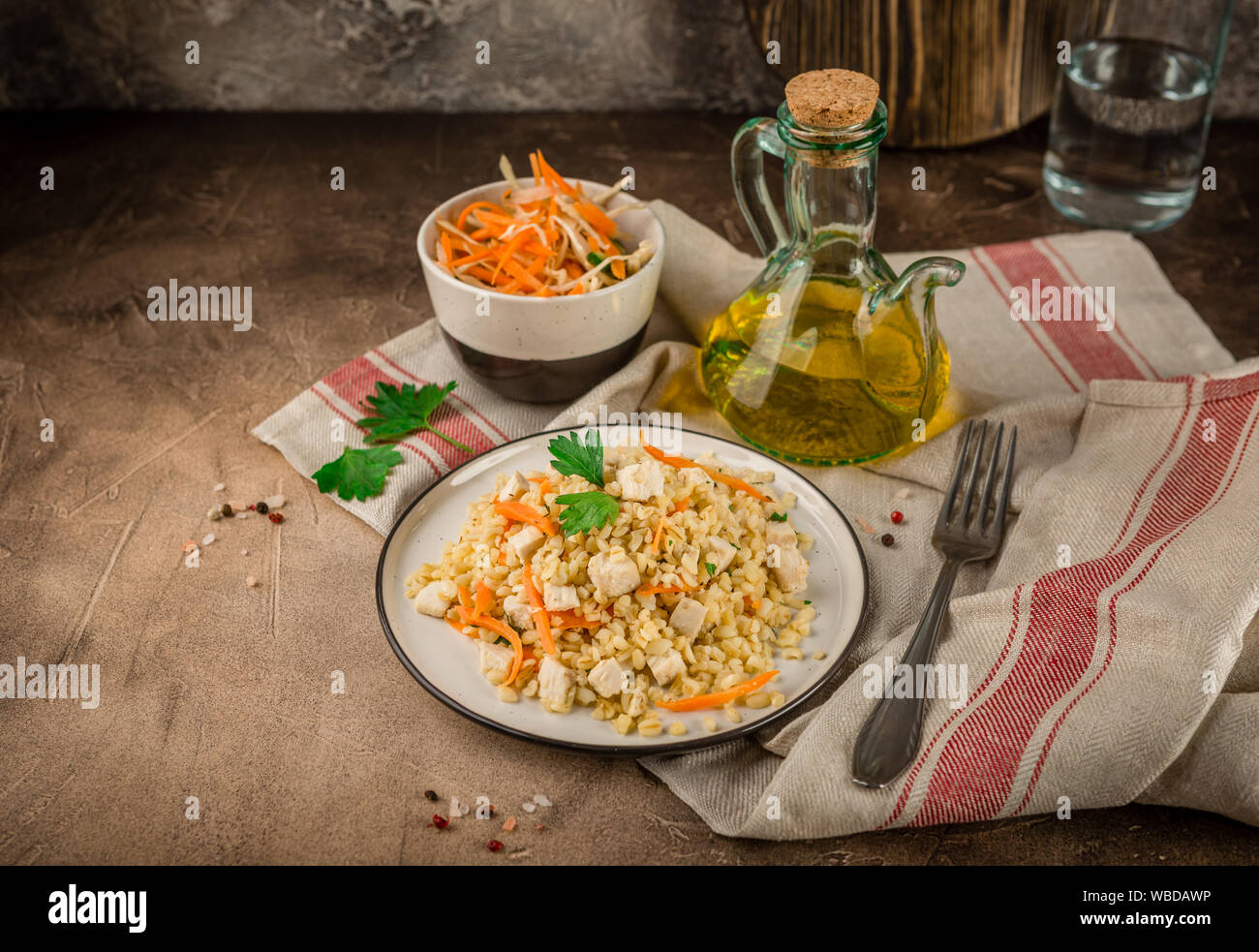Bulgur Pilaf with chicken in a plate and a bowl of coleslaw on a brown ...