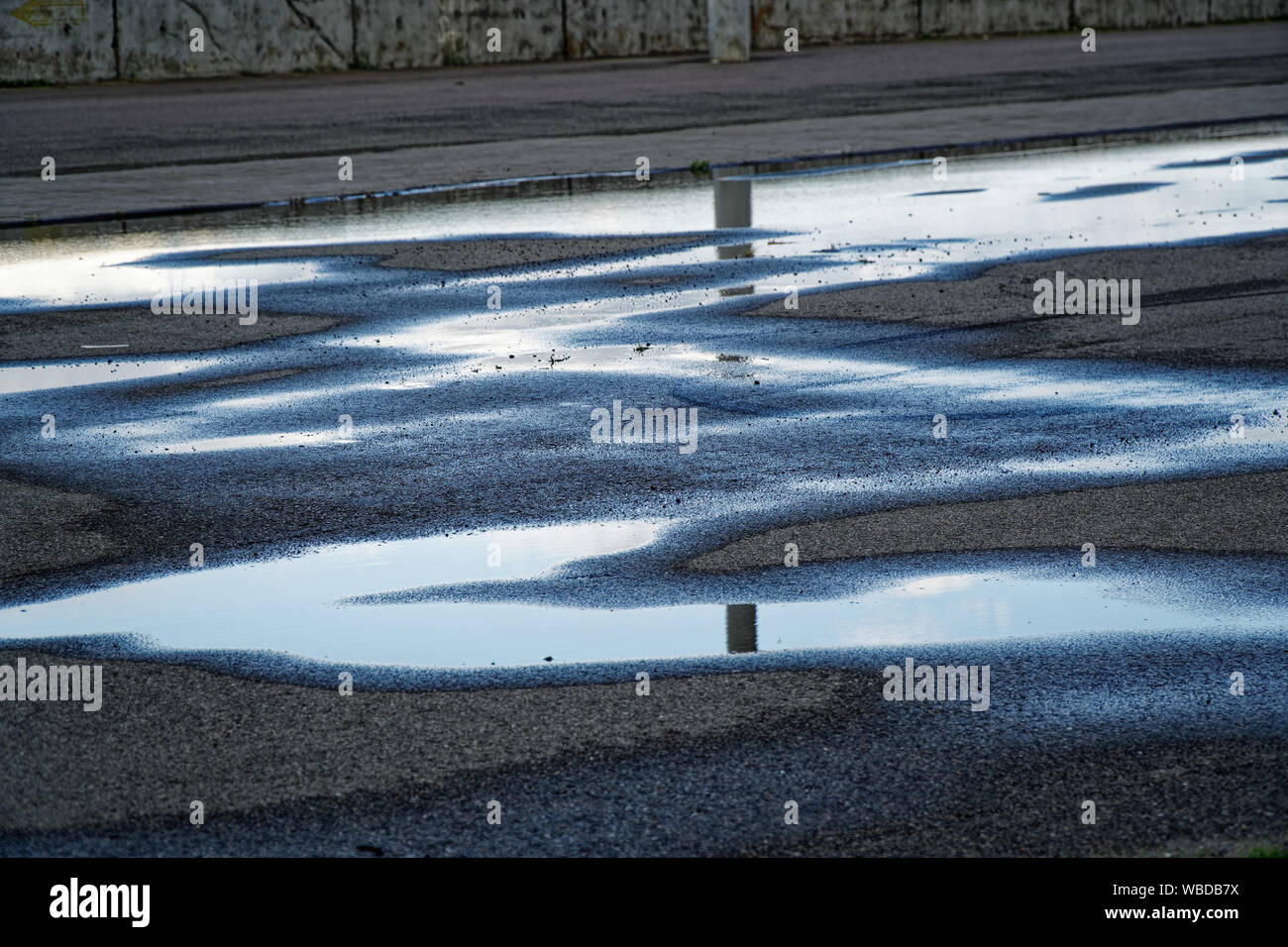 Sky reflected in a puddle of water on pavement, Early morning sunrise ...