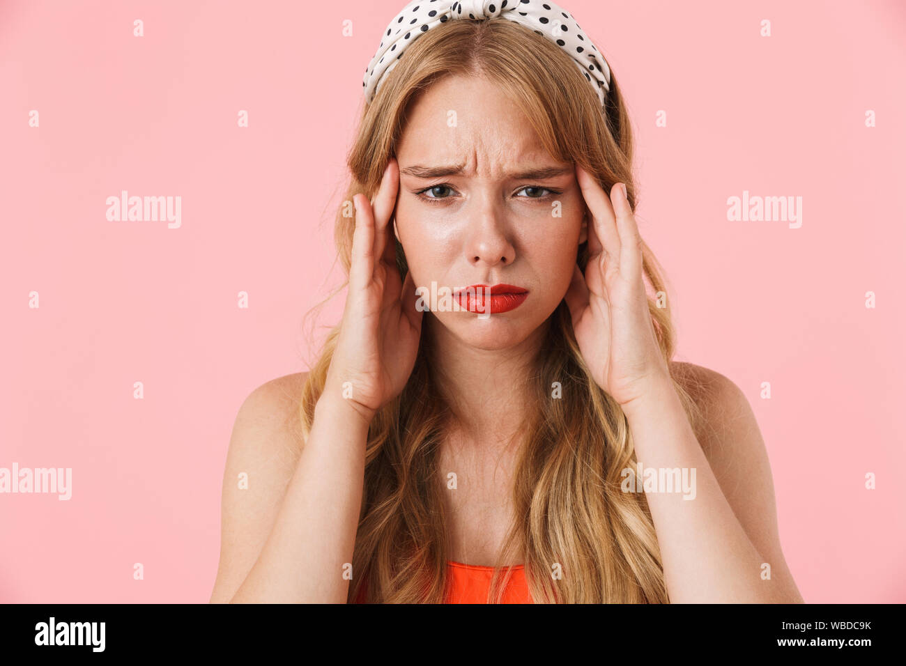 Image of serious young woman with long curly hair frowning and rubbing ...