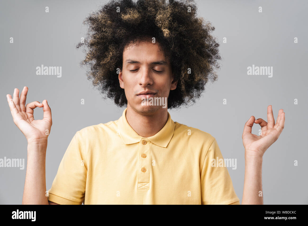 Photo of calm caucasian man with afro hairstyle meditating and keeping ...