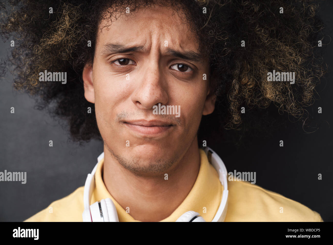 Image of a curly young confused sad teenage guy posing over grey ...