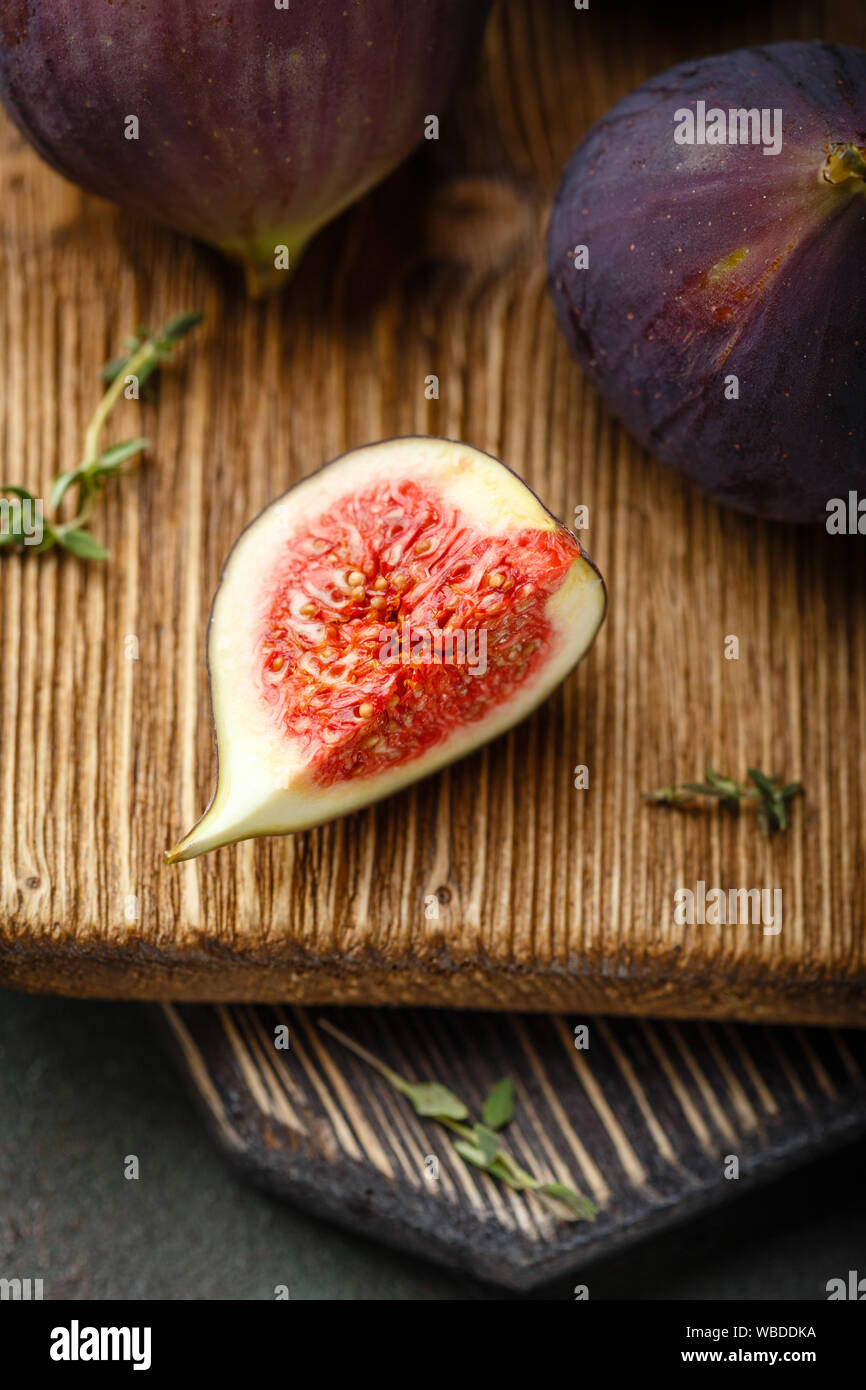 Juicy fresh whole fig fruits and one cut figs on wooden cutting board ...