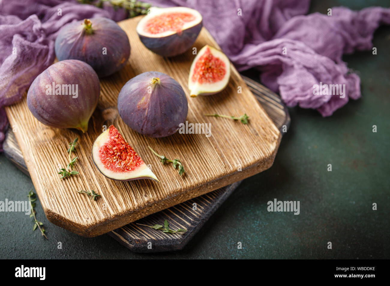 Juicy fresh whole fig fruits and one cut figs on wooden cutting board ...