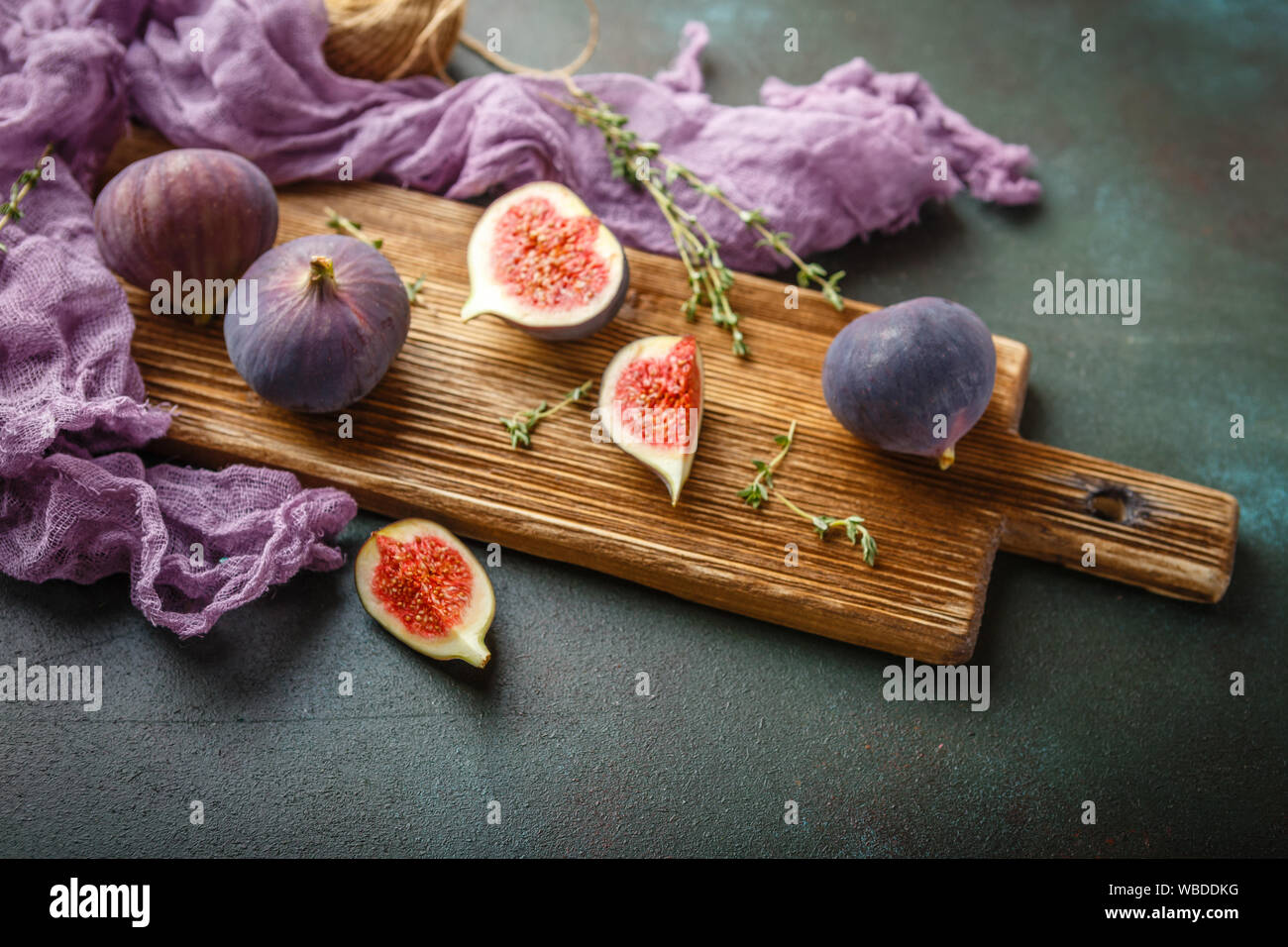 Juicy fresh whole fig fruits and one cut figs on wooden cutting board ...