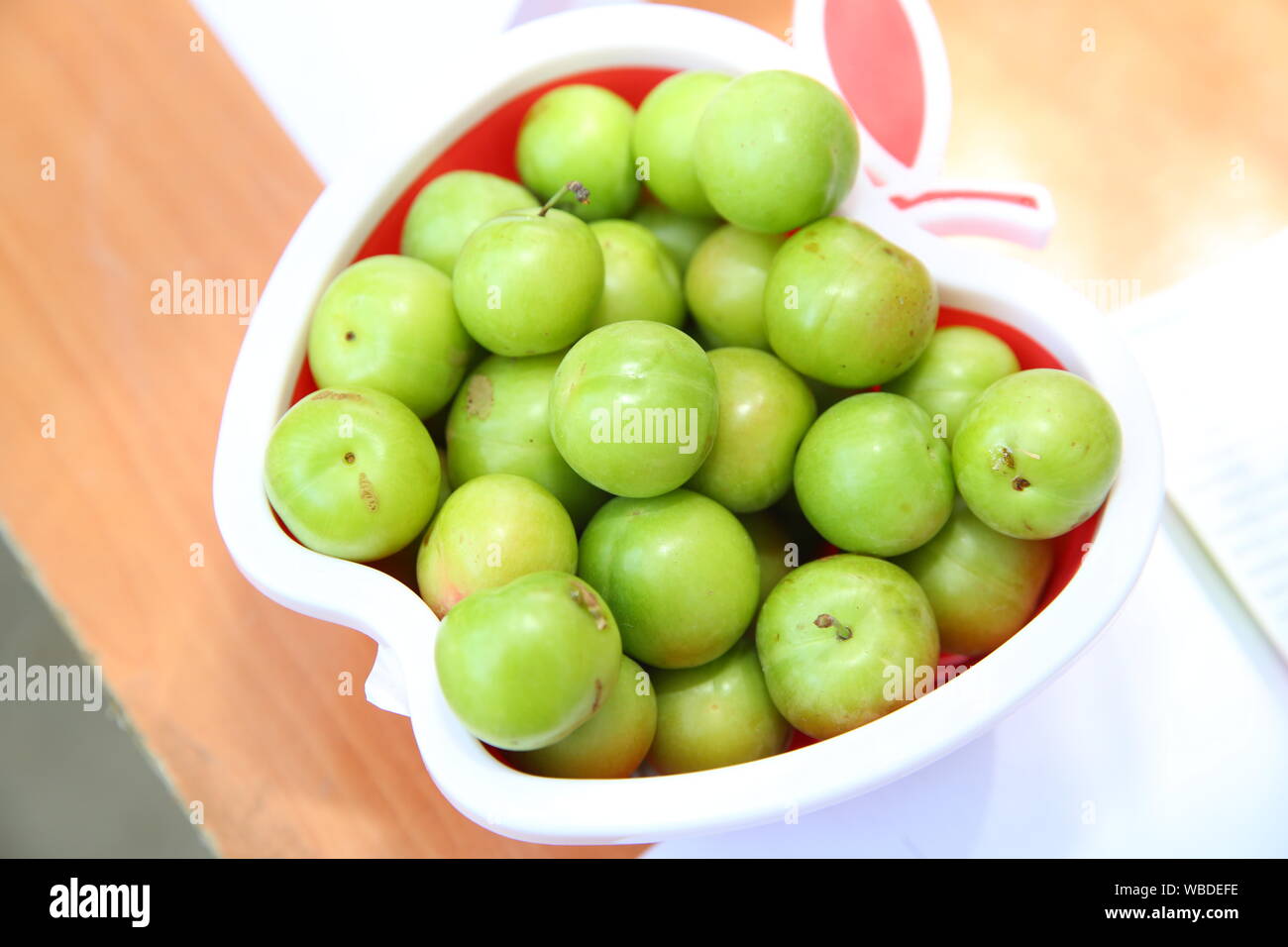 Green sour plums in the apple plate, plum pictures on the white ground ...