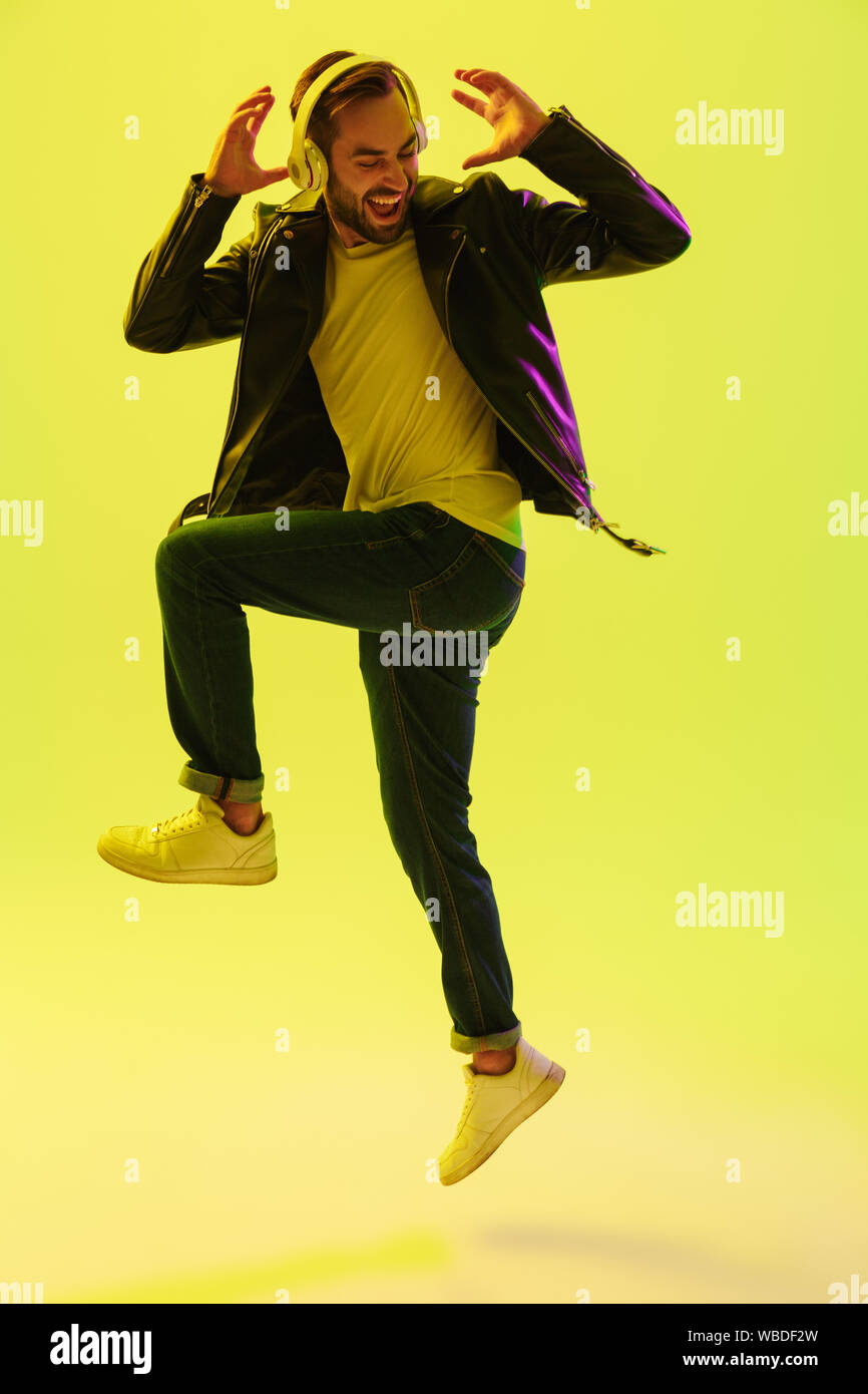 Picture of smiling emotional handsome young stylish man jumping dancing ...