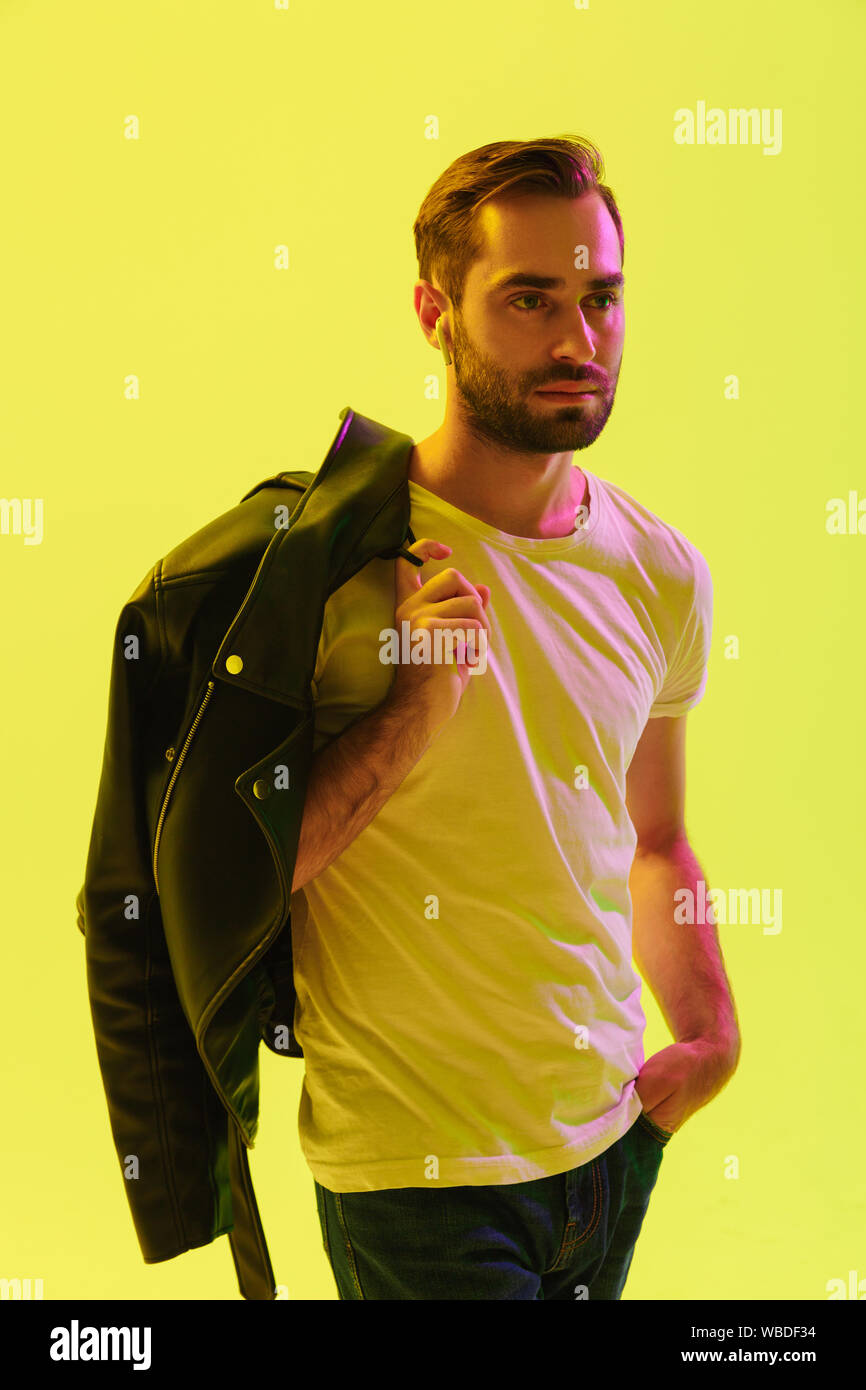 Attractive young man standing isolated over yellow background, holding ... Attractive young man standing isolated over yellow background, holding ...