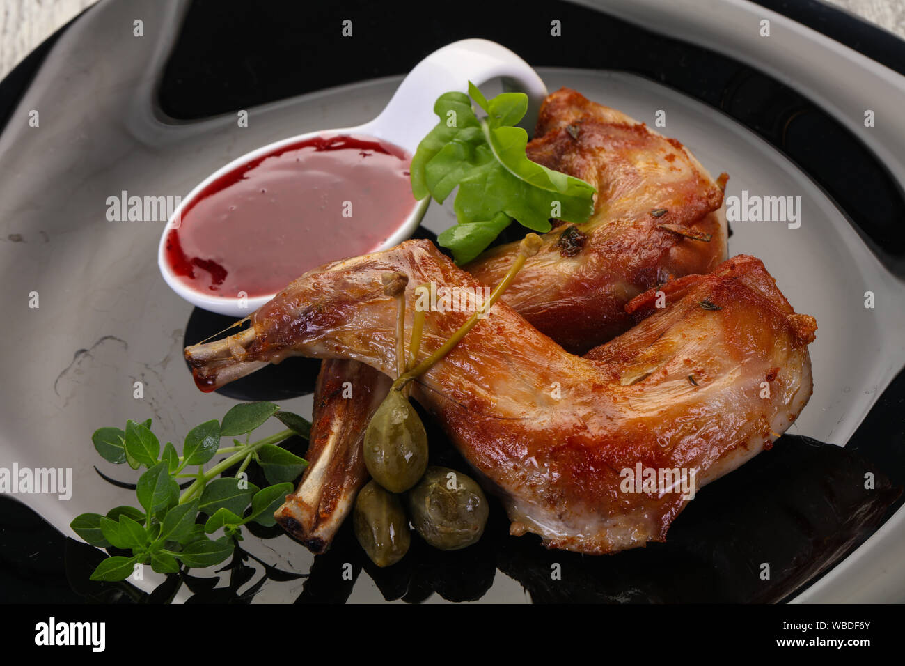 Roasted rabbit legs with cowberry sauce Stock Photo - Alamy