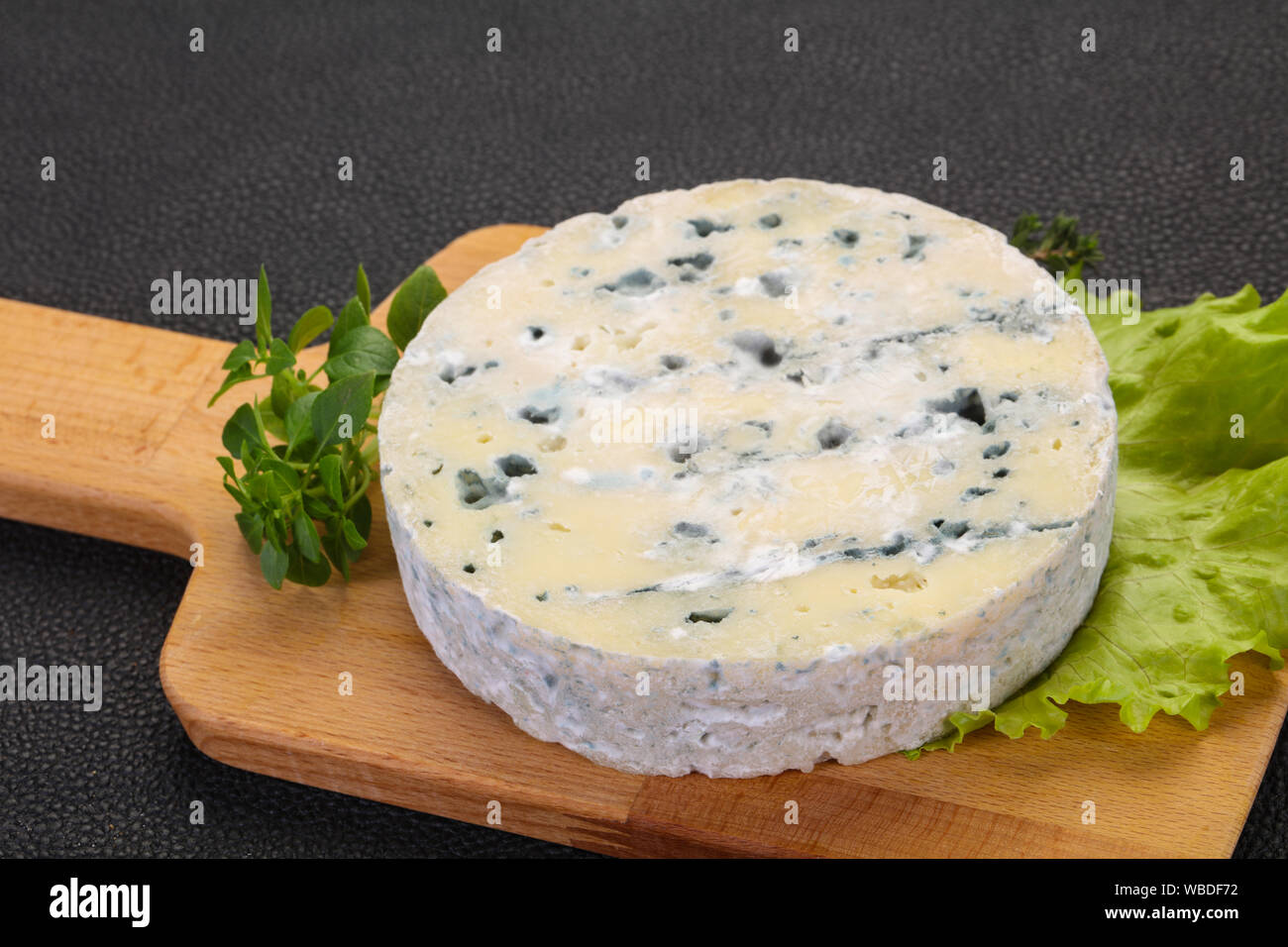 Round blue cheese with salad and basil Stock Photo - Alamy