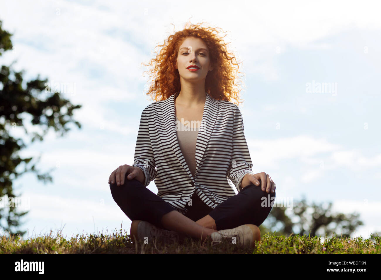 Relaxed female person sitting in yoga pose Stock Photo - Alamy
