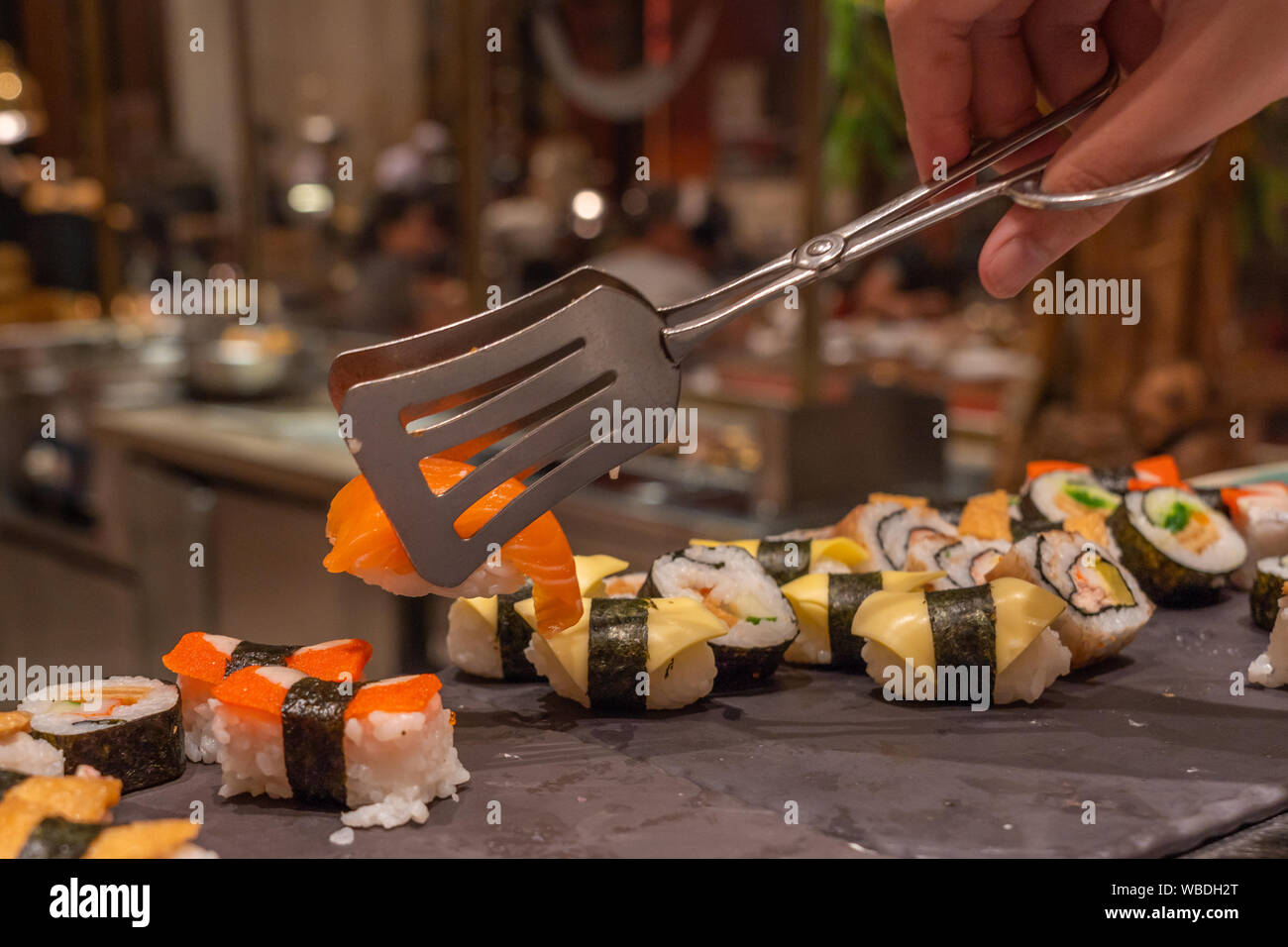 Human hand picking sashimi sushi in luxury Japanese buffet restaurant ...